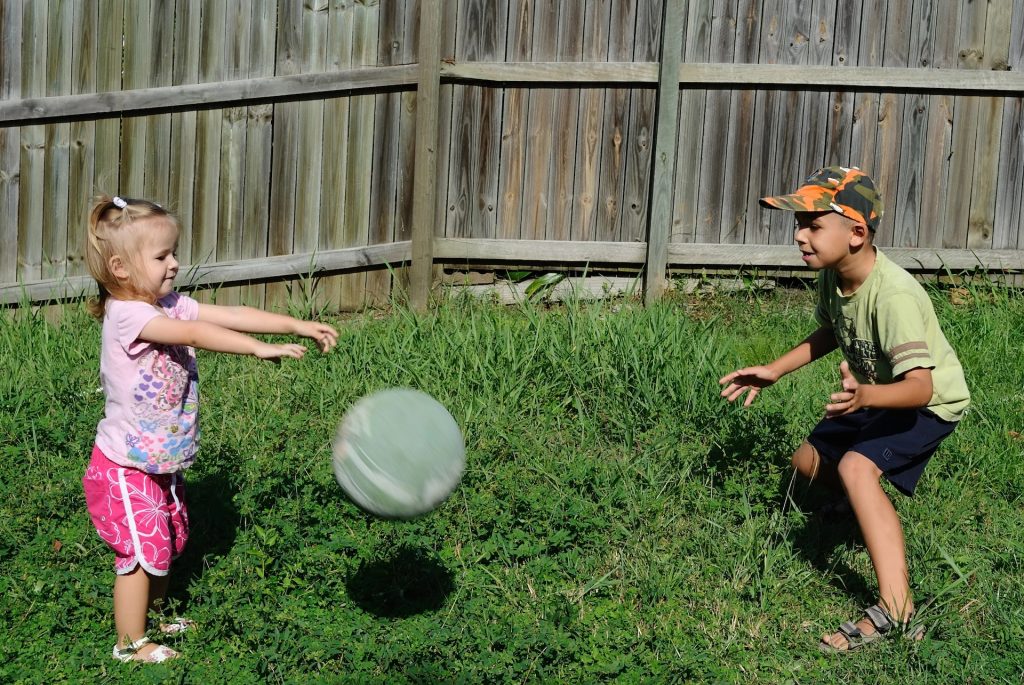 Two kids playing ball in a backyard • Martin Septic Service